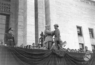 Mussolini hands over a medal of value to a soldier during the ...